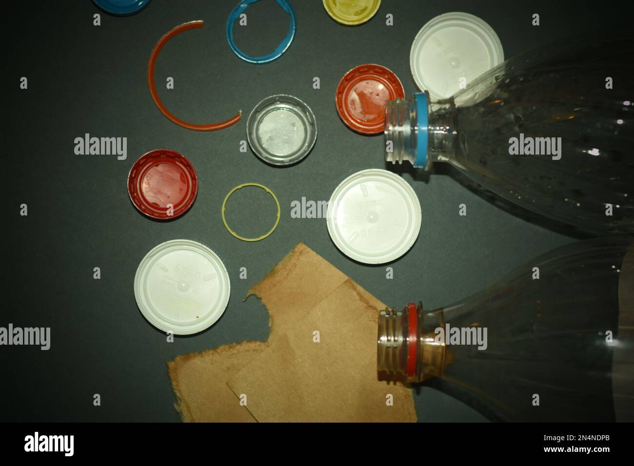 Plastic bottle caps, bottles and cardboard on a gray background ...