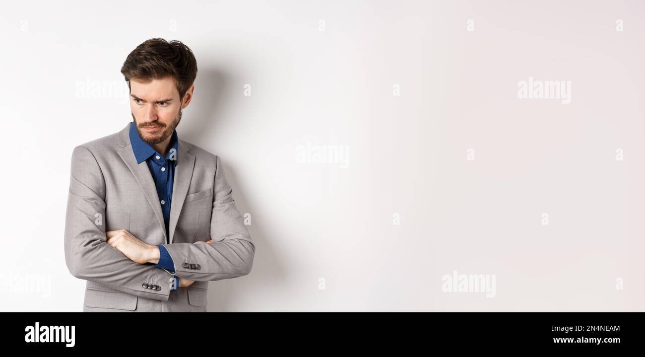 Moody guy in suit looking aside with unfair face, cross arms on chest ...