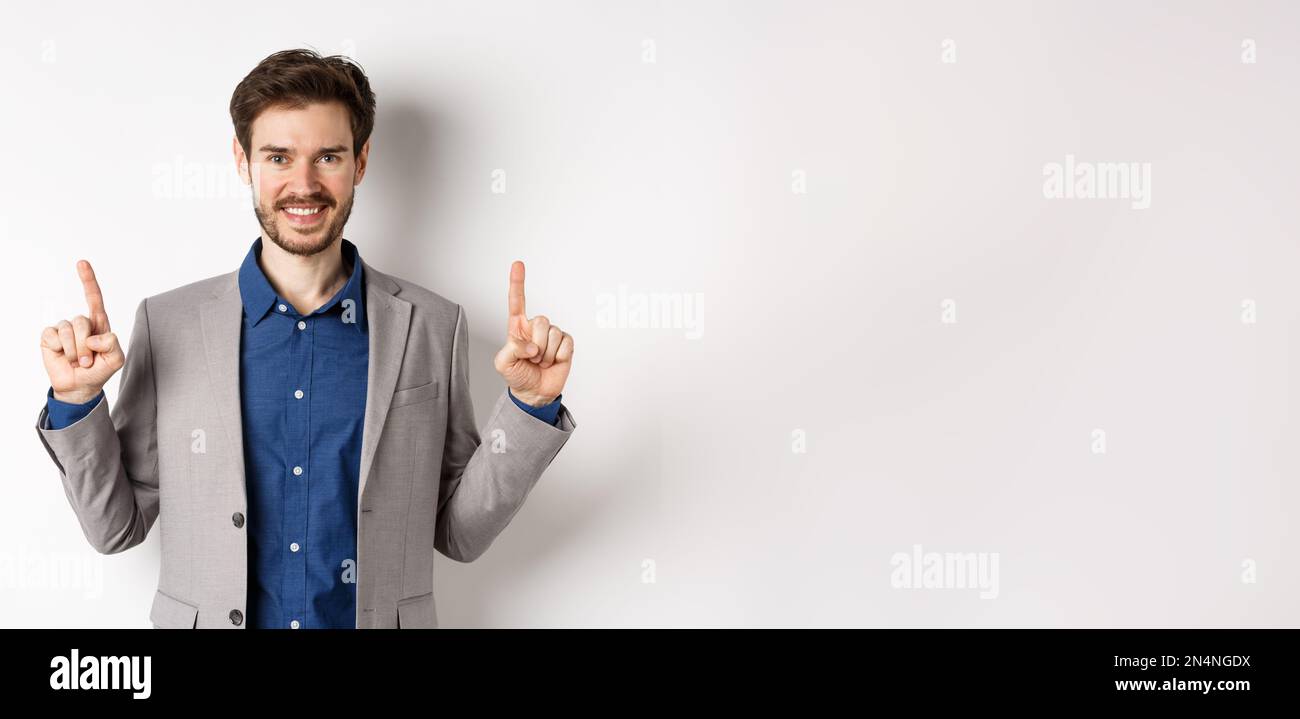Confident successful businessman pointing fingers up, smiling and ...