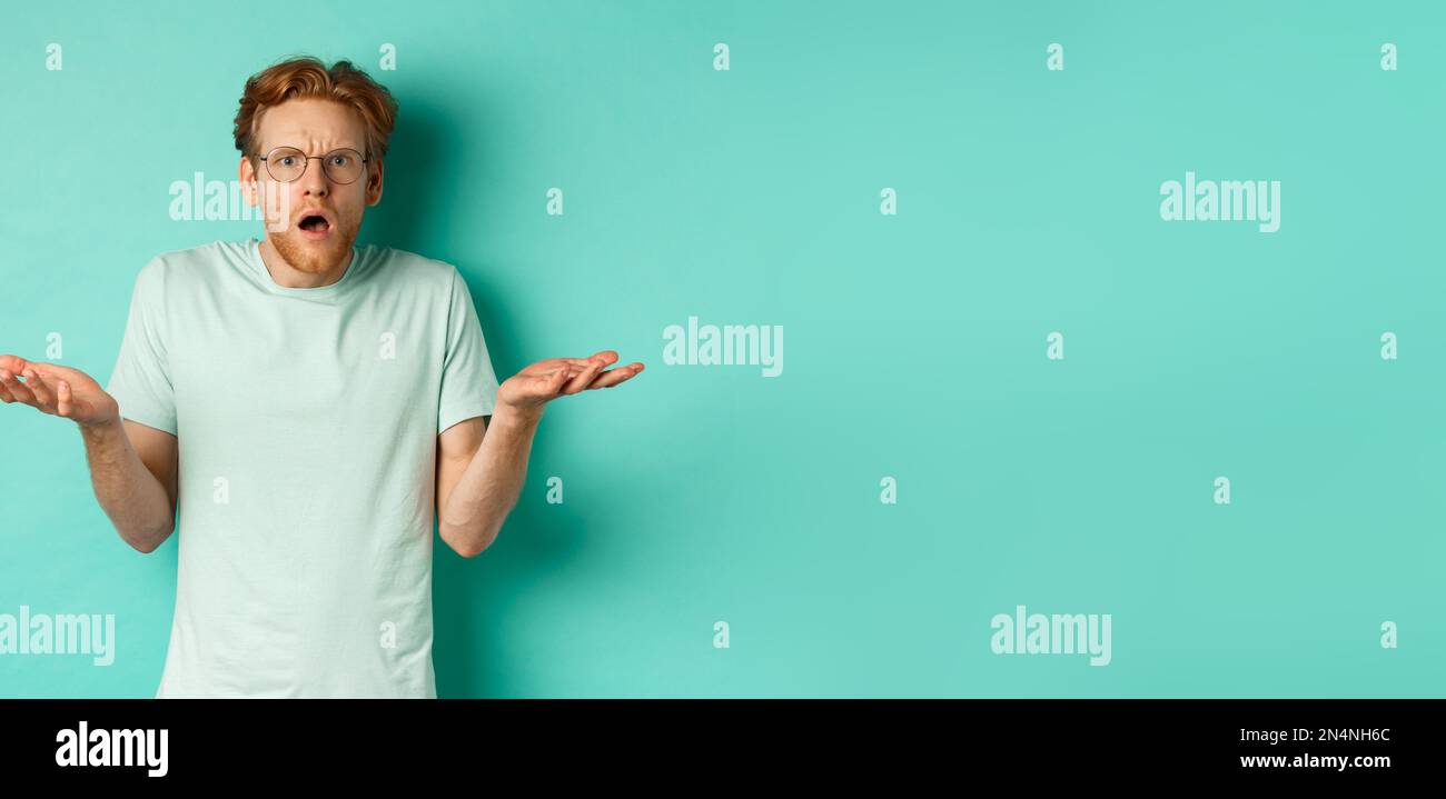 Confused and shocked guy with red messy hair and glasses, shrugging and ...