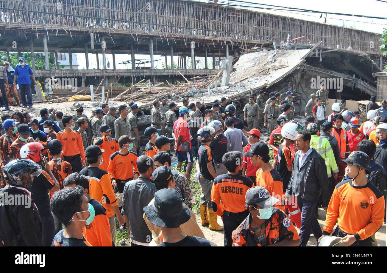 Rescuers search for survivors after a building under construction, background, collapsed in ...