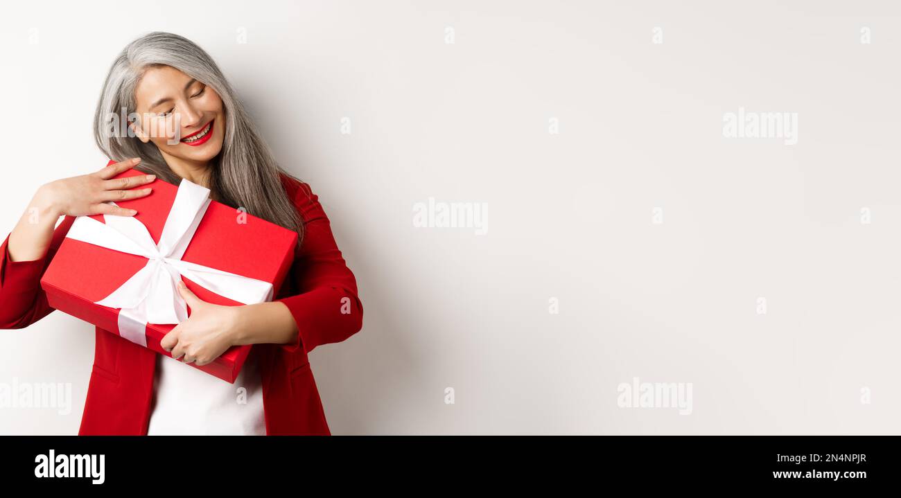 Valentine day concept. Beautiful asian senior woman hugging box with ...