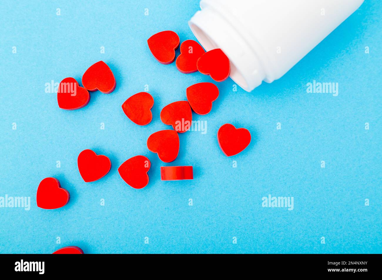 Red heart shaped pills with plastic bottle on blue background.Concept ...