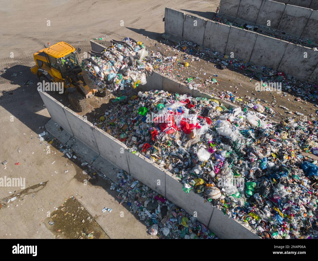 Yellow skid steer loader moving wooden waste material, shaking out a ...