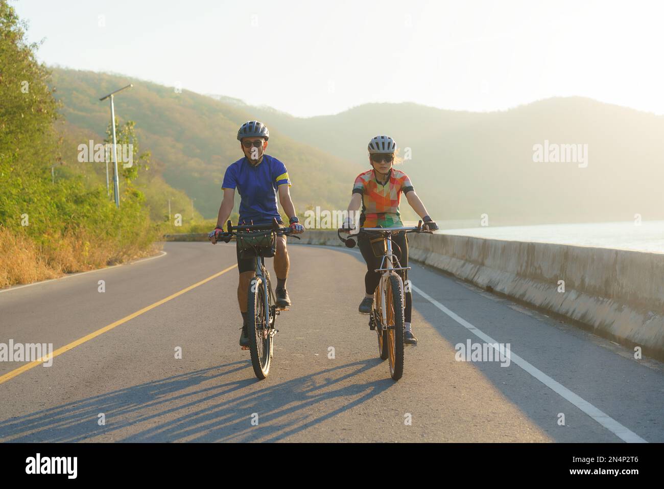 Asian cyclist couple riding together for exercise around the lake in ...