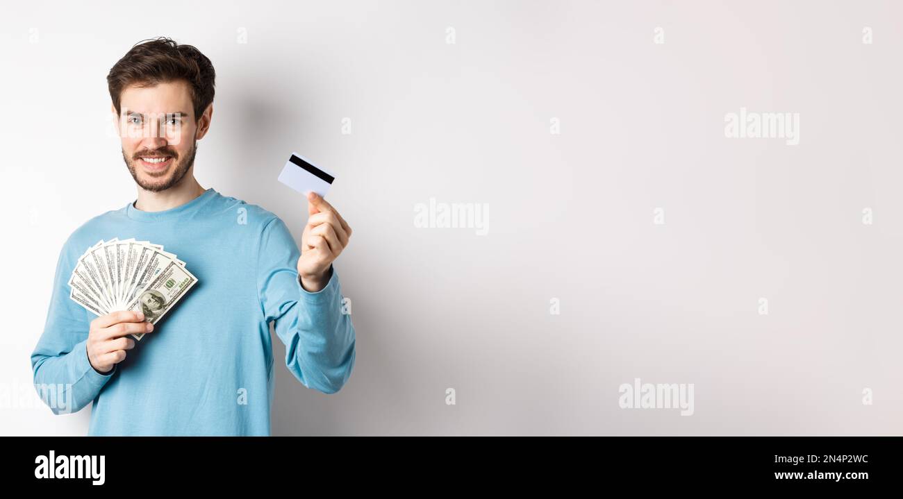 Handsome young man smiling and offering payment in cash and contactless ...