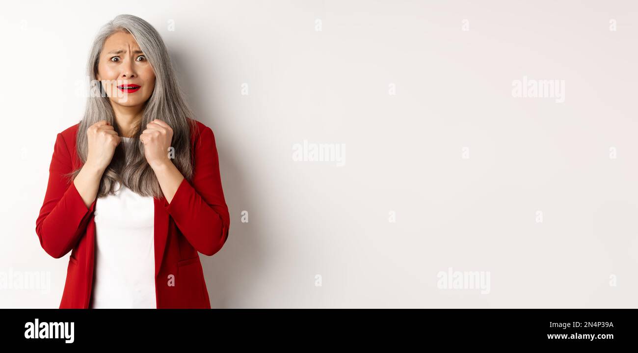 Business people. Scared mature asian woman looking terrified, trembling ...