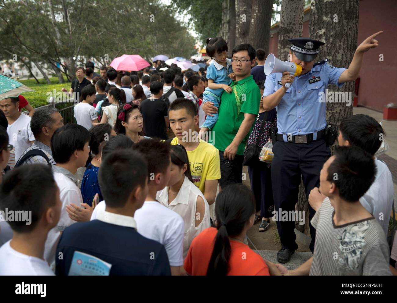 A Chinese policeman uses a loud speaker to order visitors to line up to ...