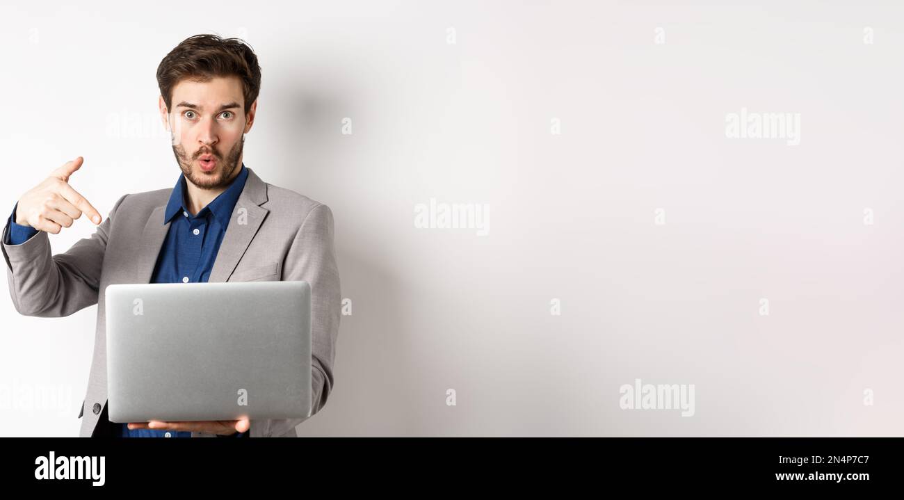 Excited handsome man asking to look here, pointing at laptop screen ...