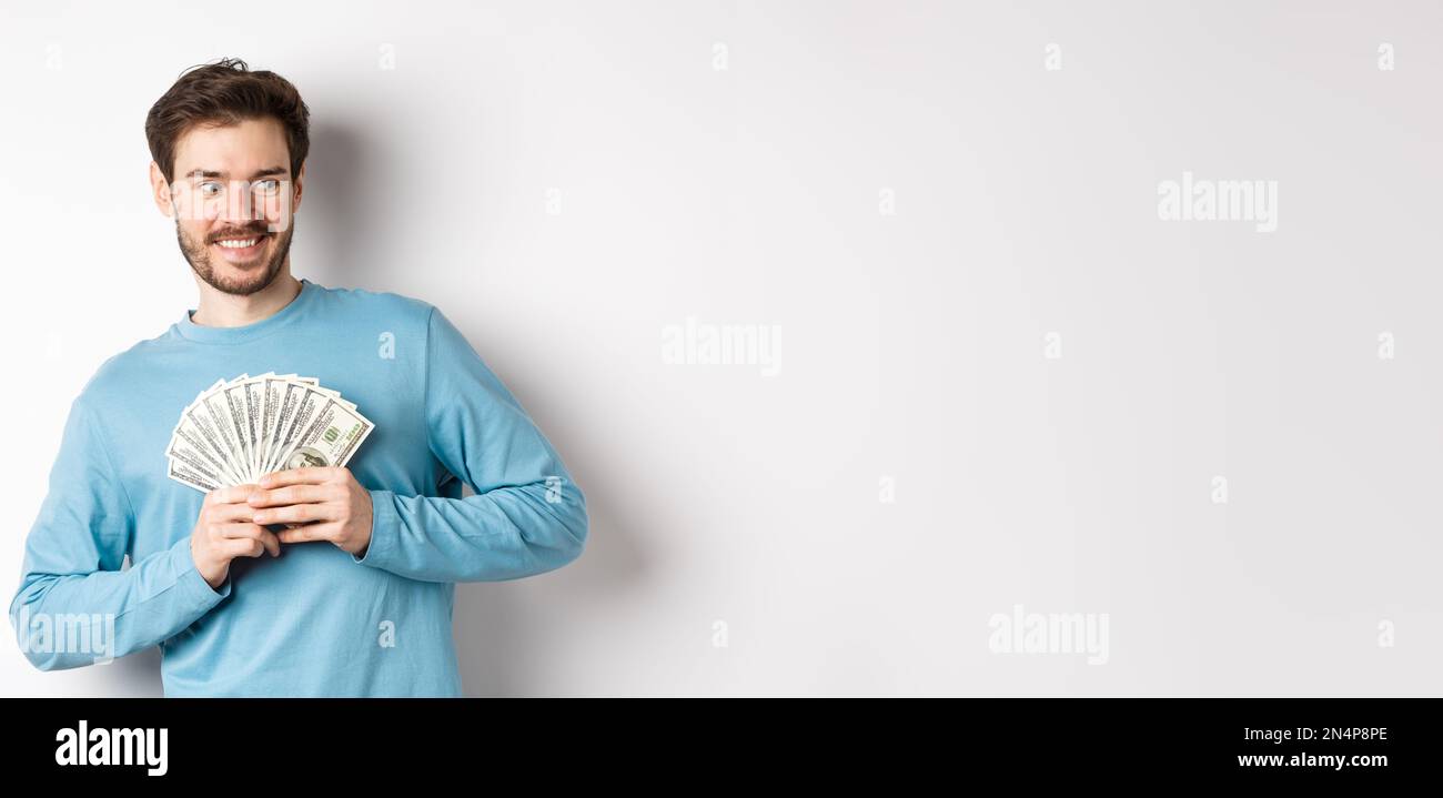 Greedy smiling man showing money and looking right, thinking about ...