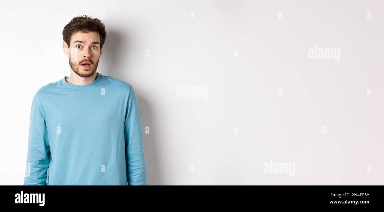 Confused caucasian guy drop jaw and stare startled at camera, standing ...