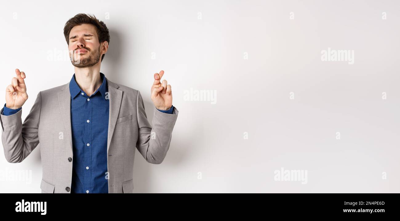 Nervous businessman in suit begging god, holding fingers crossed with ...