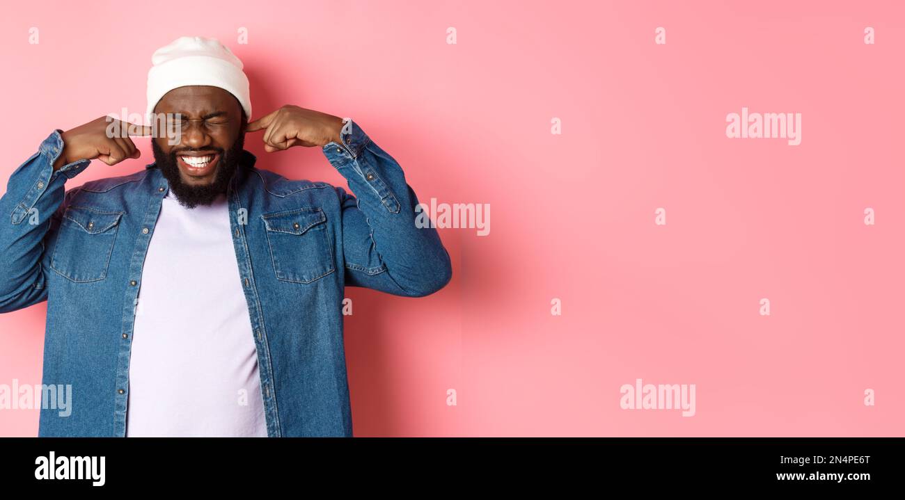 Displeased african-american man shut ears and grimacing from loud awful ...