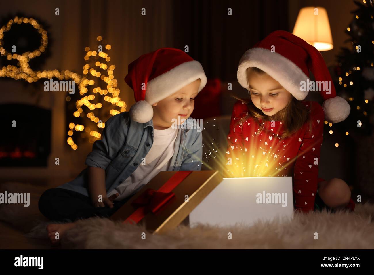 Cute children opening gift box in room decorated for Christmas Stock ...