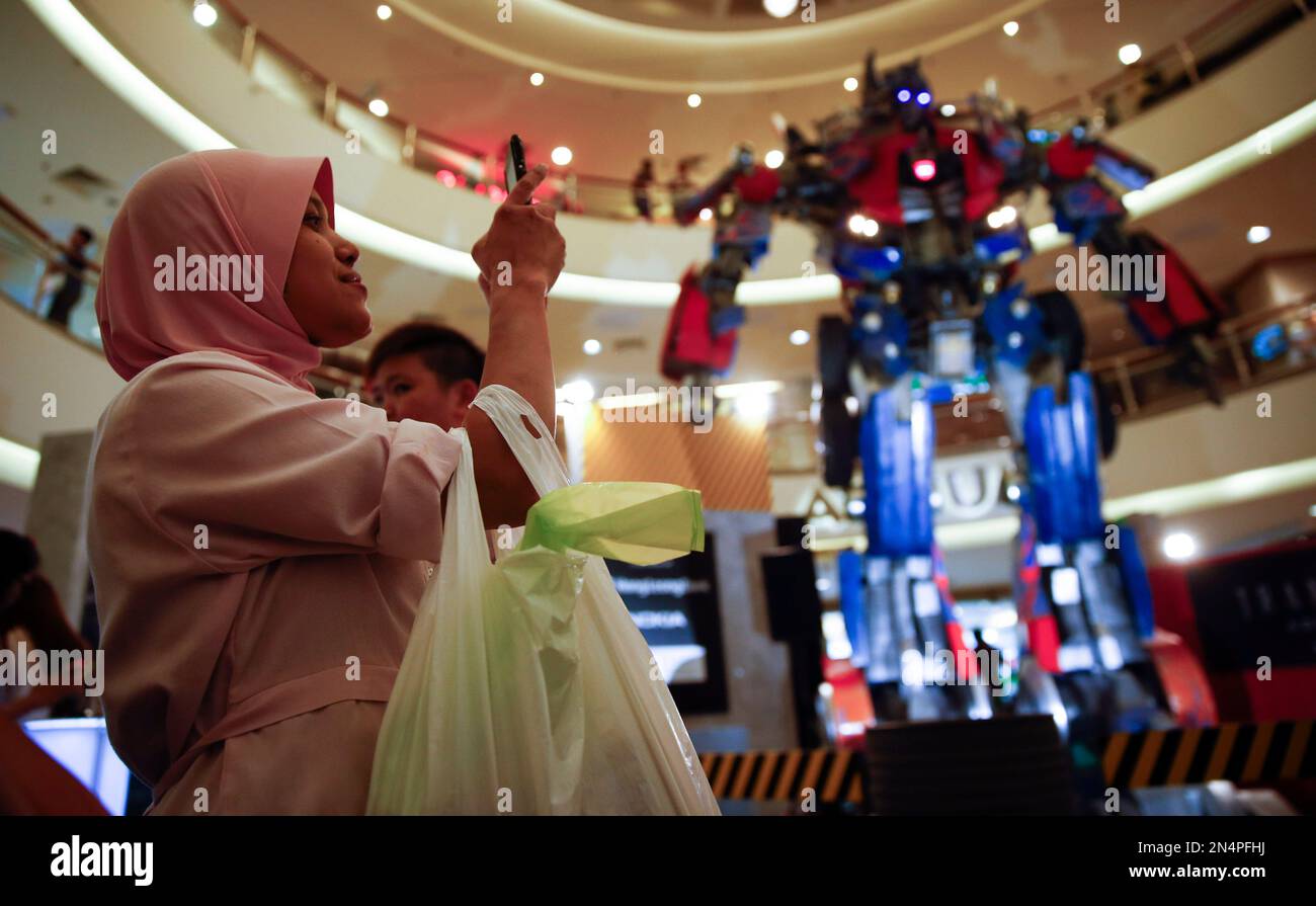 A shopper takes a picture in front of a giant Transformer figure on ...