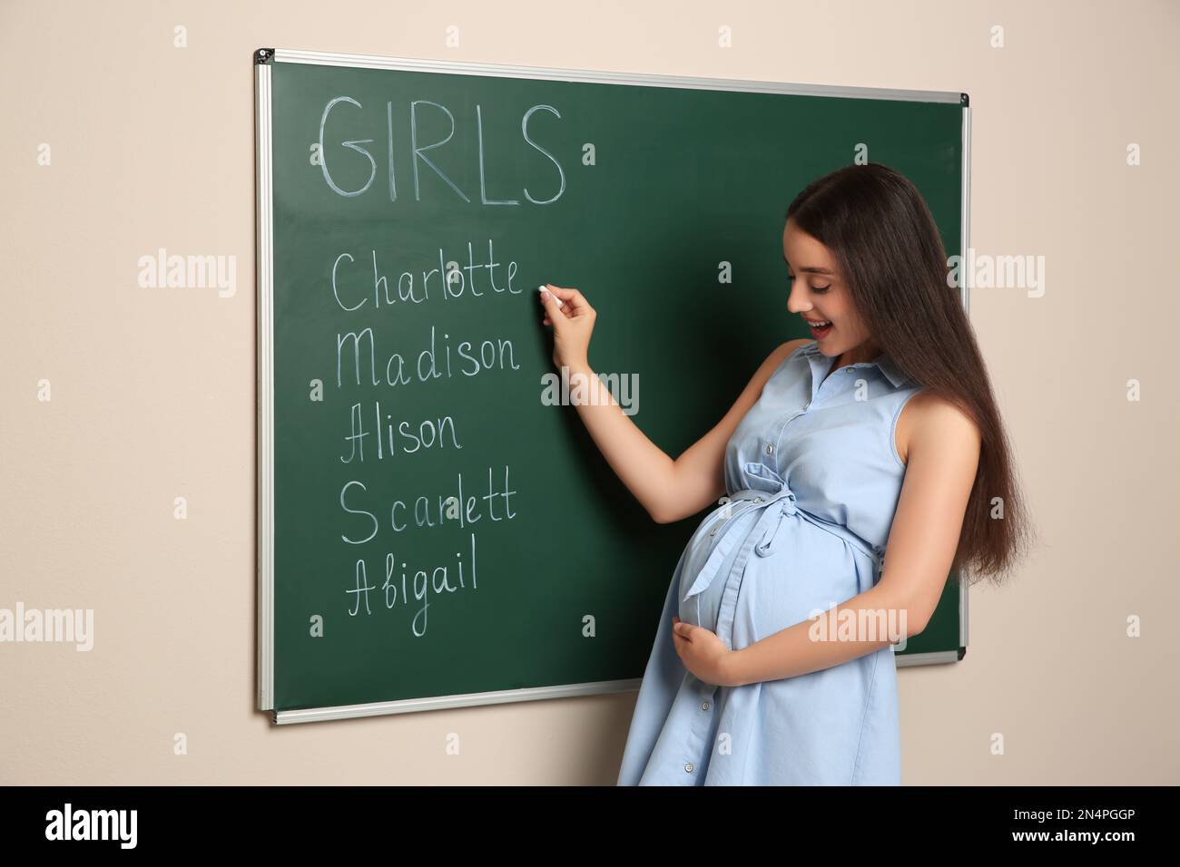 Pregnant woman writing different baby names on green chalkboard Stock ...