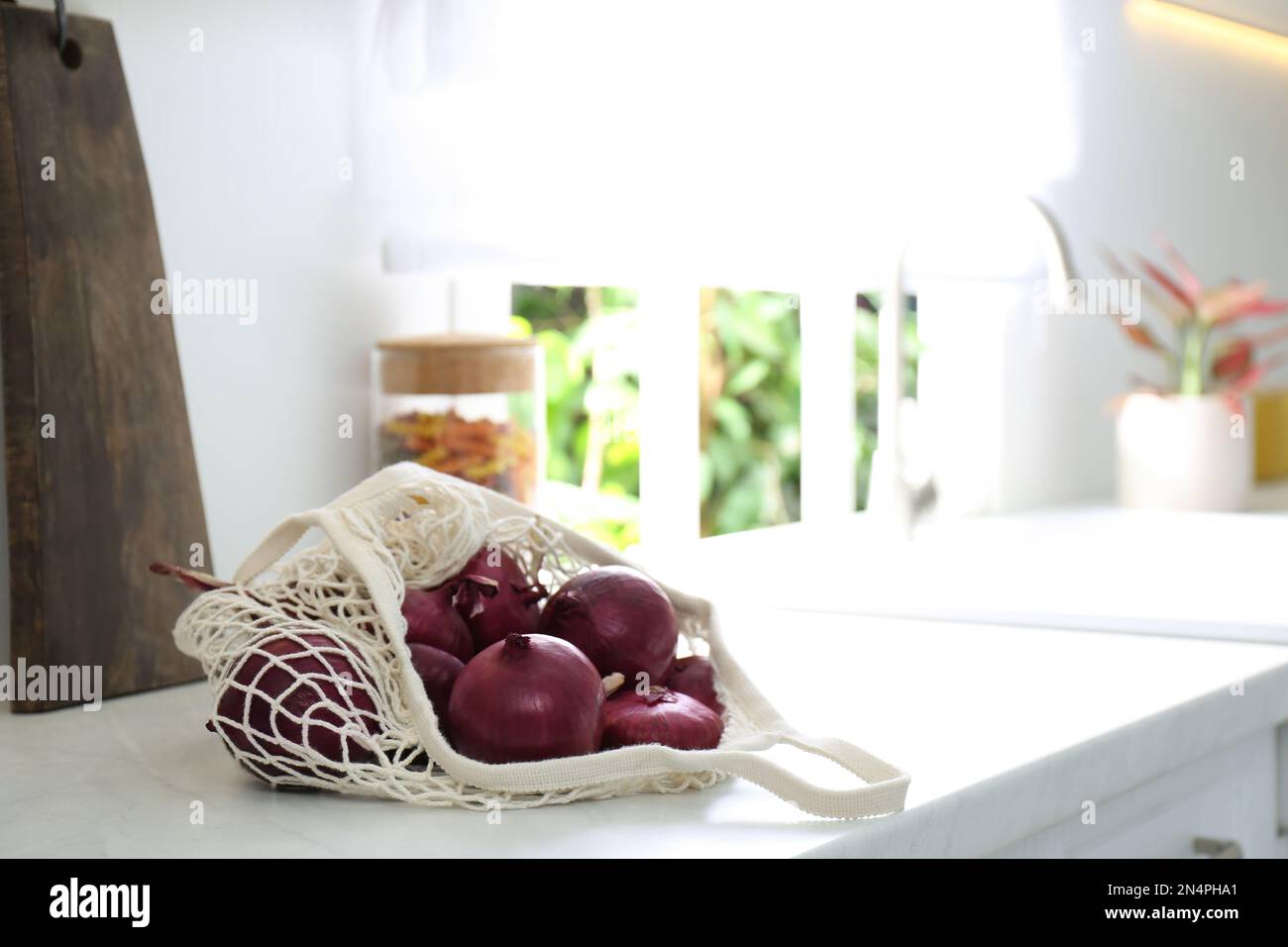 Red onions in mesh tote bag on countertop of kitchen Stock Photo - Alamy