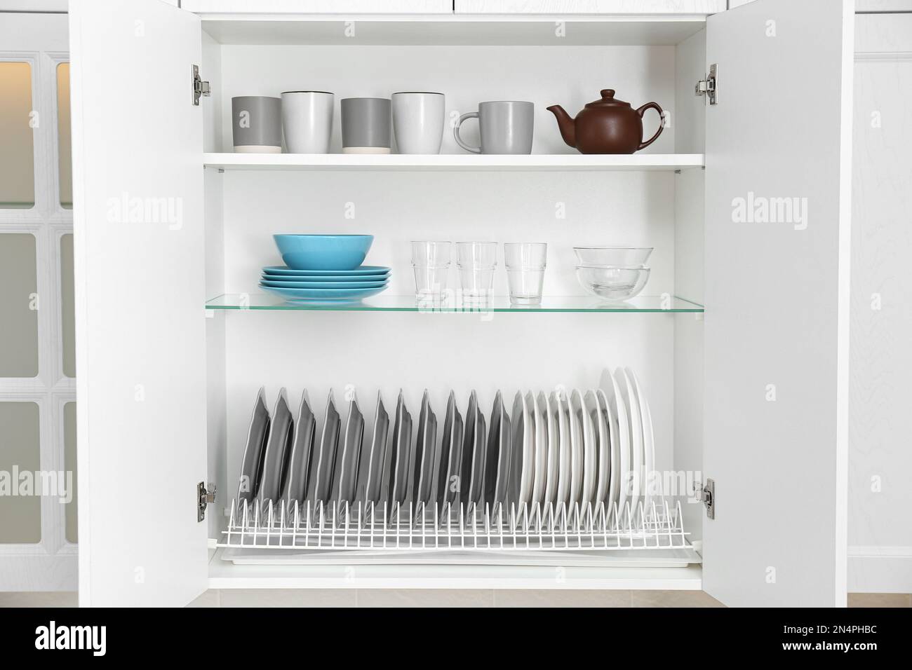 Open cabinet with different clean dishware in kitchen Stock Photo - Alamy