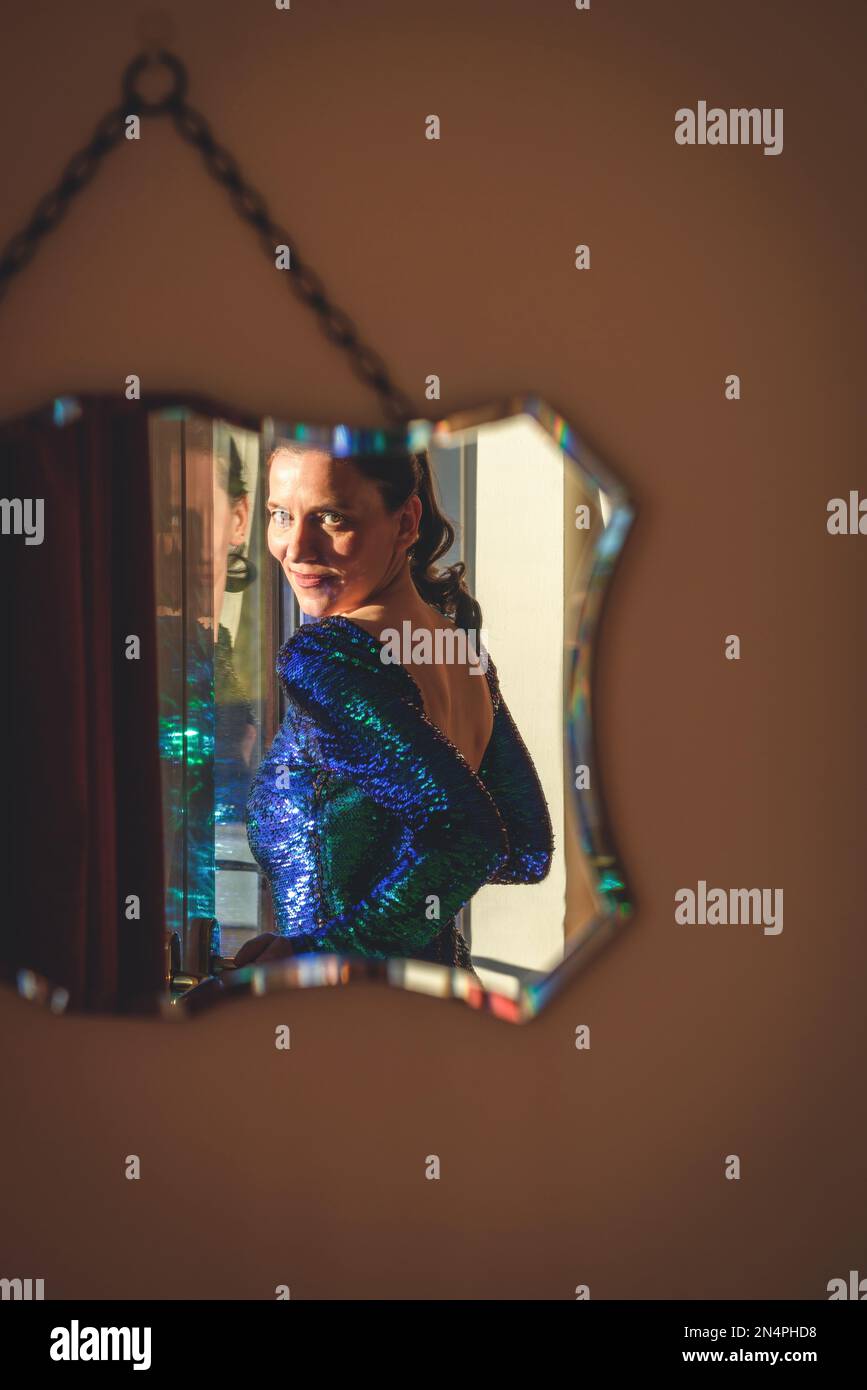 Reflection in a wall mounted mirror of a woman smiling wearing a blue ...