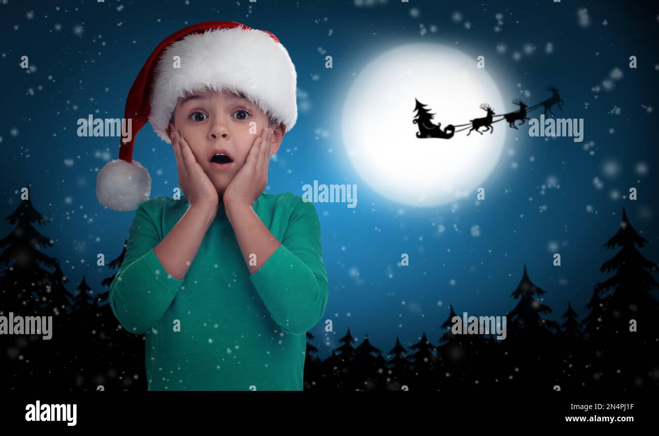 Cute little child and Santa Claus flying in his sleigh against moon sky ...