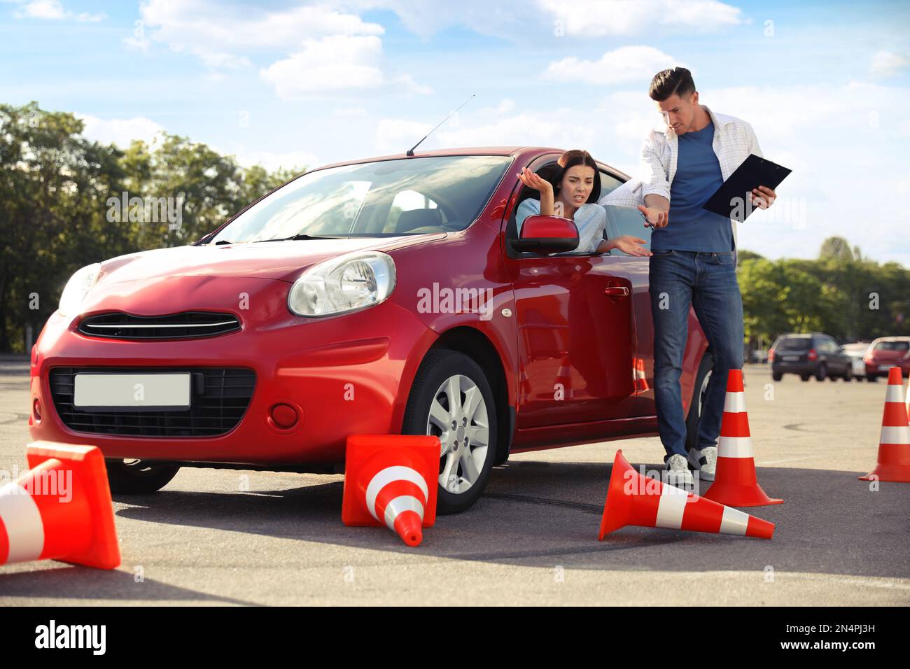 Stressed young woman in car near instructor and fallen traffic cones ...