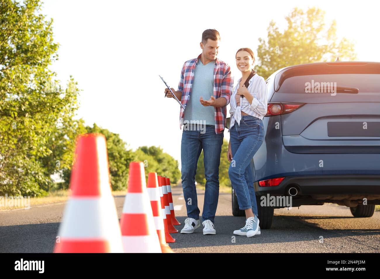 Instructor with clipboard and his student near car outdoors. Driving ...