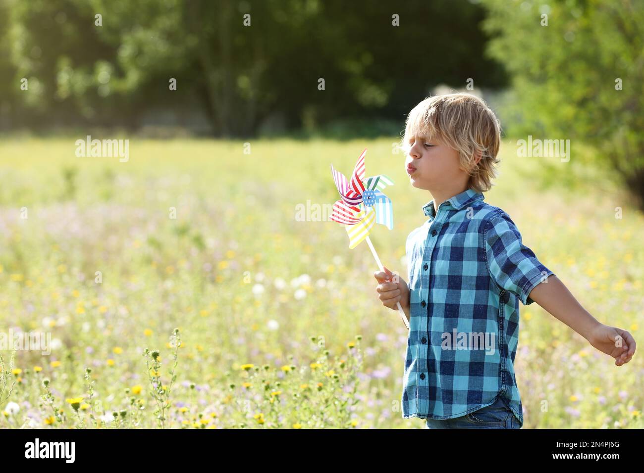 Cute little boy with pinwheel outdoors, space for text. Child spending ...