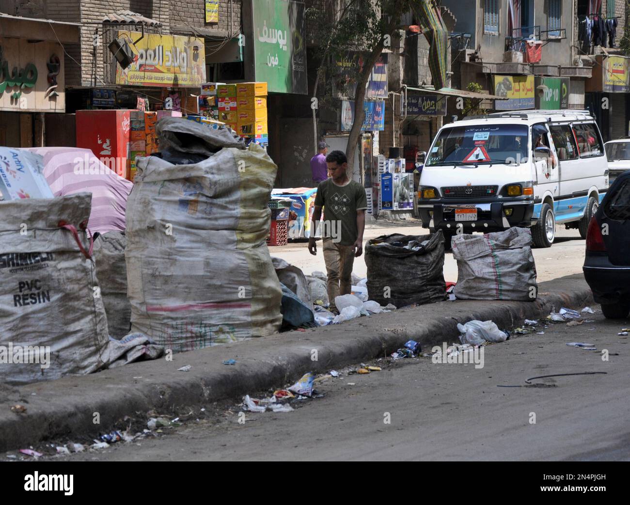 A man walks through garbage left on a street in Cairo's neighborhood of ...
