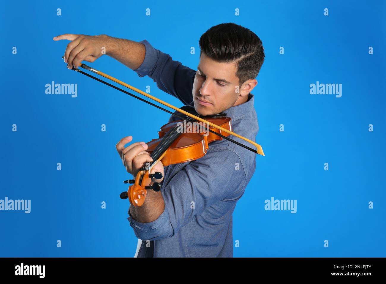 Man playing violin on light blue background Stock Photo - Alamy