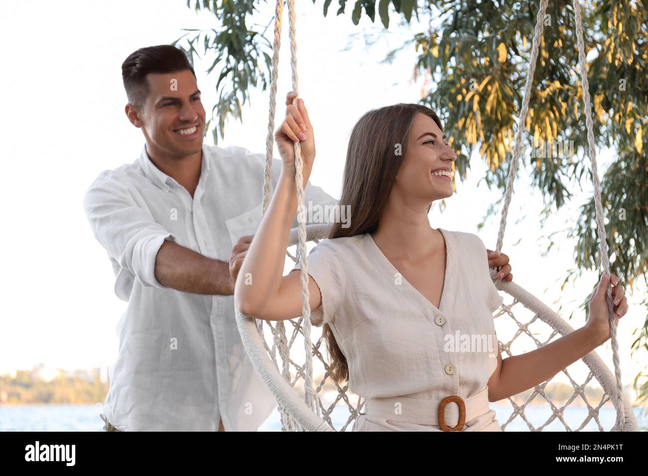 Young woman in hammock chair and her boyfriend on beach. Summer ...
