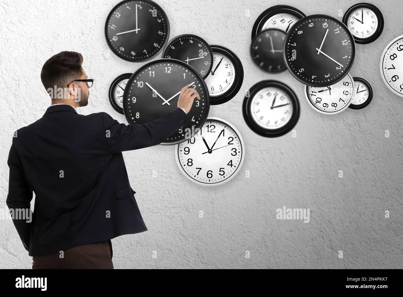 Time management concept. Businessman and different clocks on light grey ...