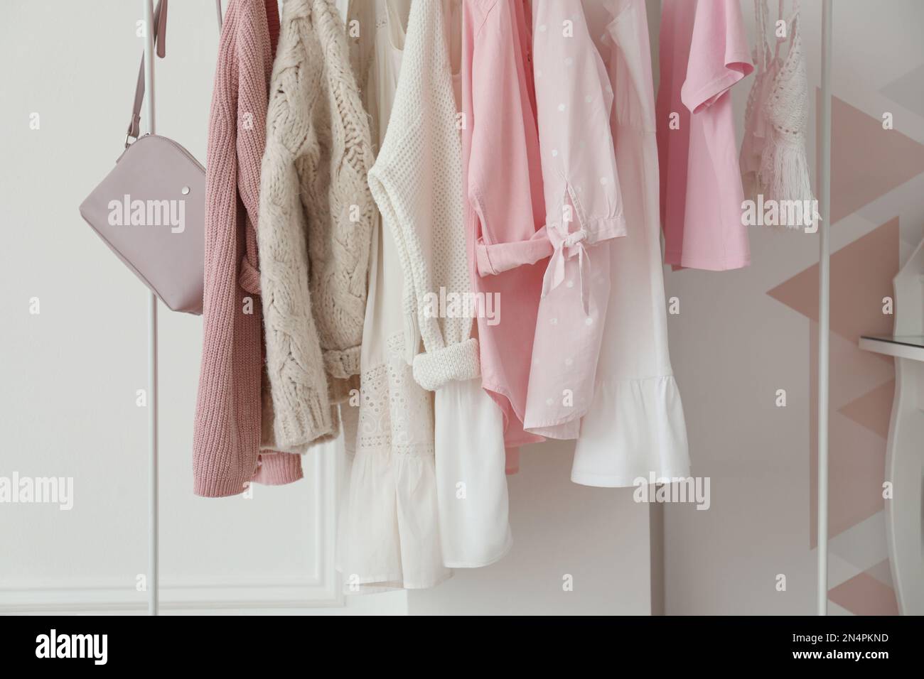 Rack with stylish clothes near white wall in dressing room Stock Photo ...