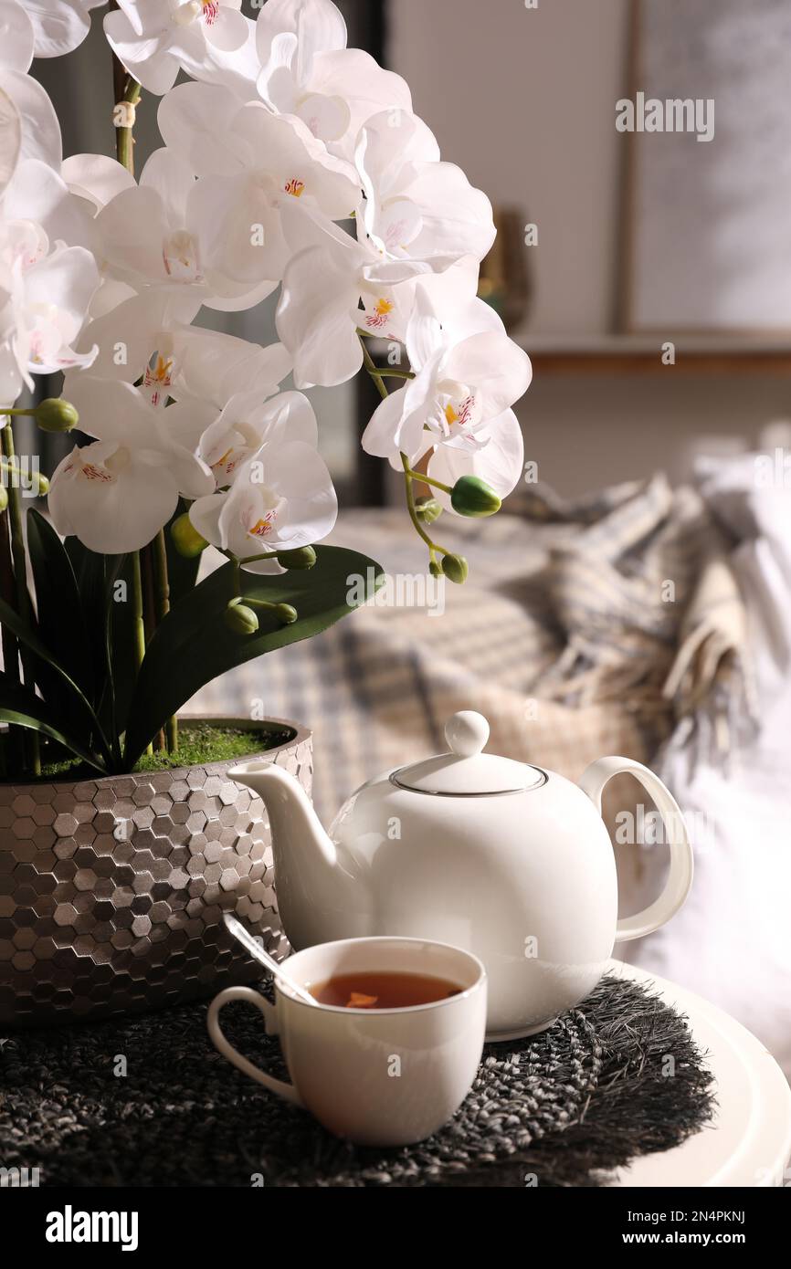 Beautiful white orchids and tea set on table in room Stock Photo - Alamy