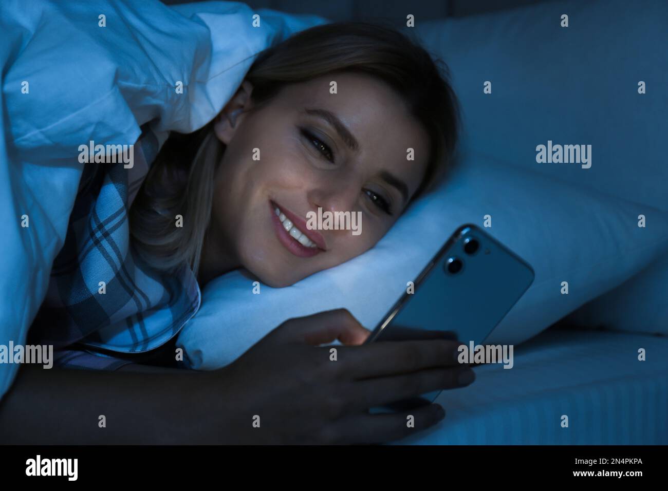Young woman using smartphone in bed at night. Nomophobia and sleeping ...