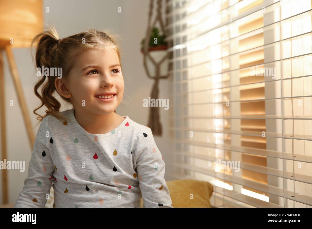 Portrait of cute little girl near window at home Stock Photo - Alamy