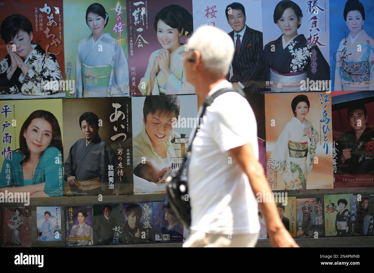 A man walks past posters of singers of enka, a quintessentially ...