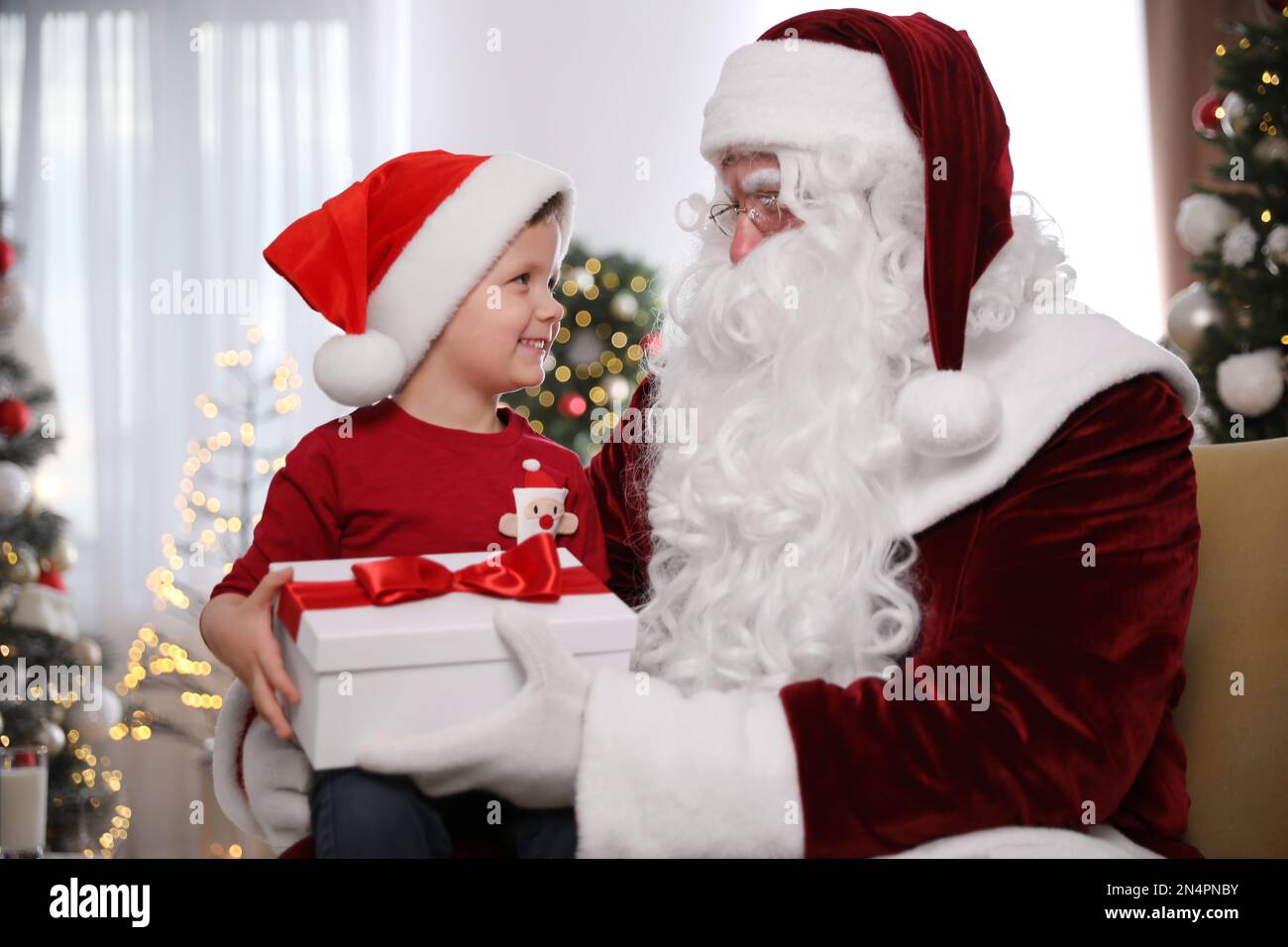 Santa Claus giving present to little boy in room decorated for ...