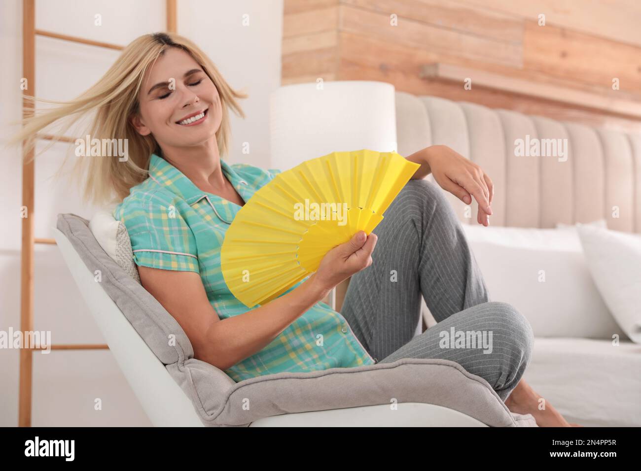 Woman enjoying air flow from hand fan at home. Summer heat Stock Photo ...