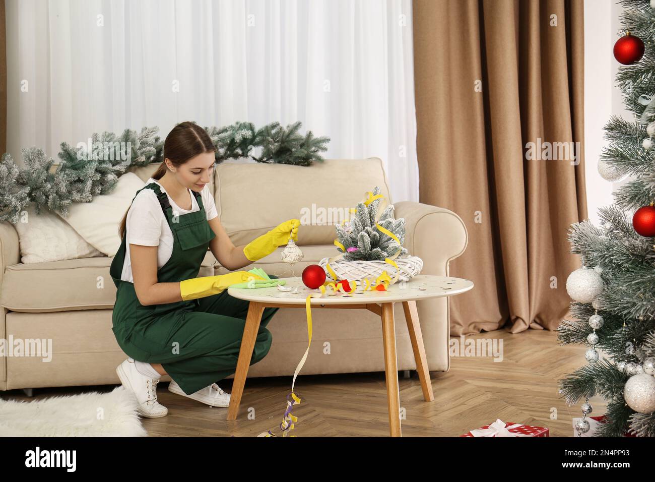 Woman from cleaning service working in messy room after New Year party ...