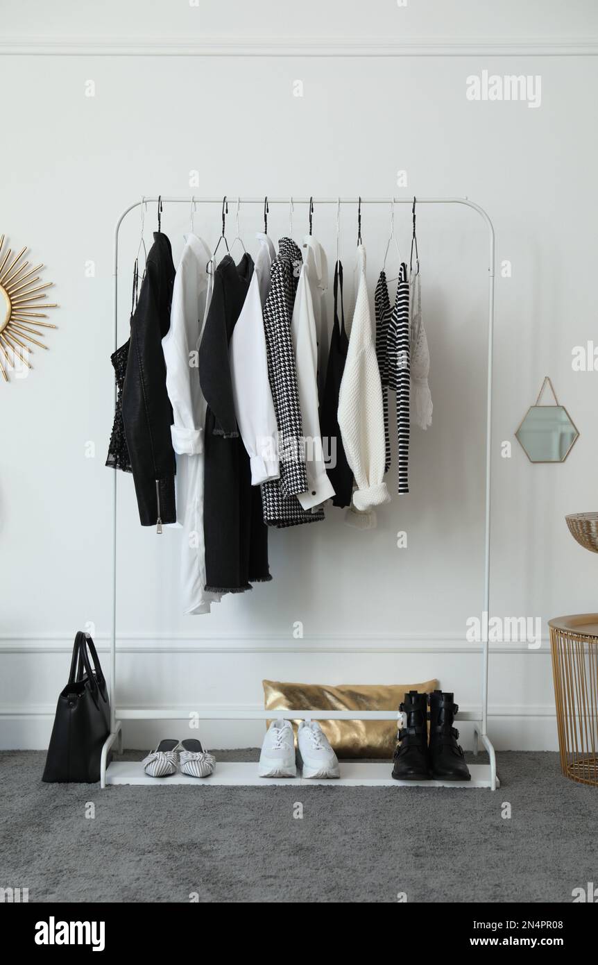 Rack with stylish clothes near white wall in dressing room Stock Photo ...