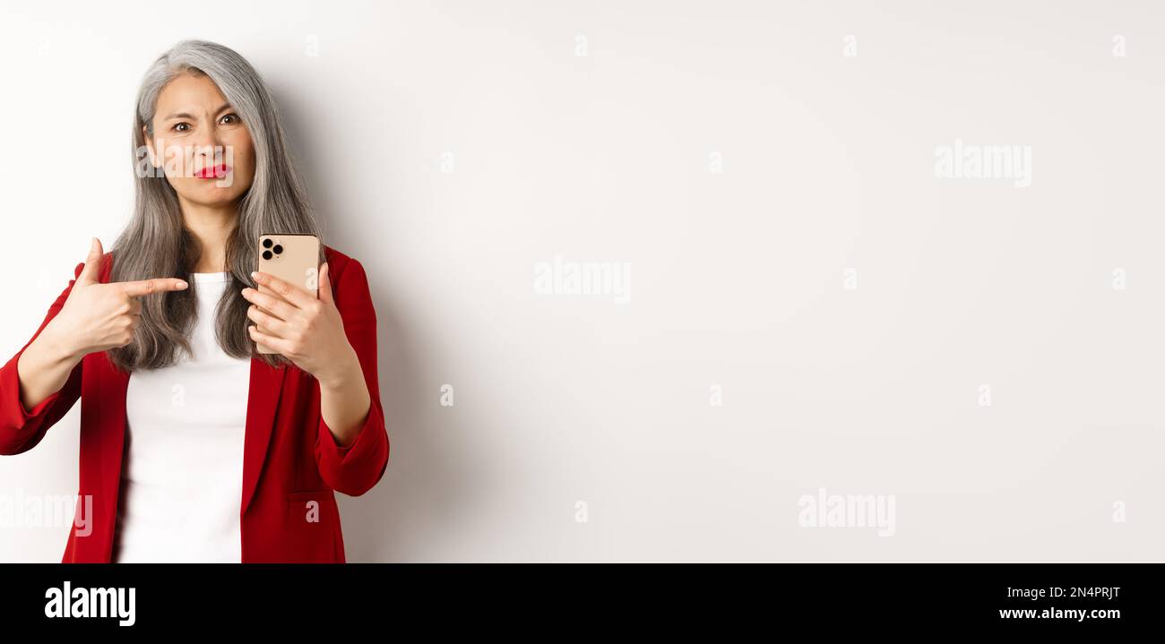 Disappointed mature asian woman complaining, pointing finger at ...