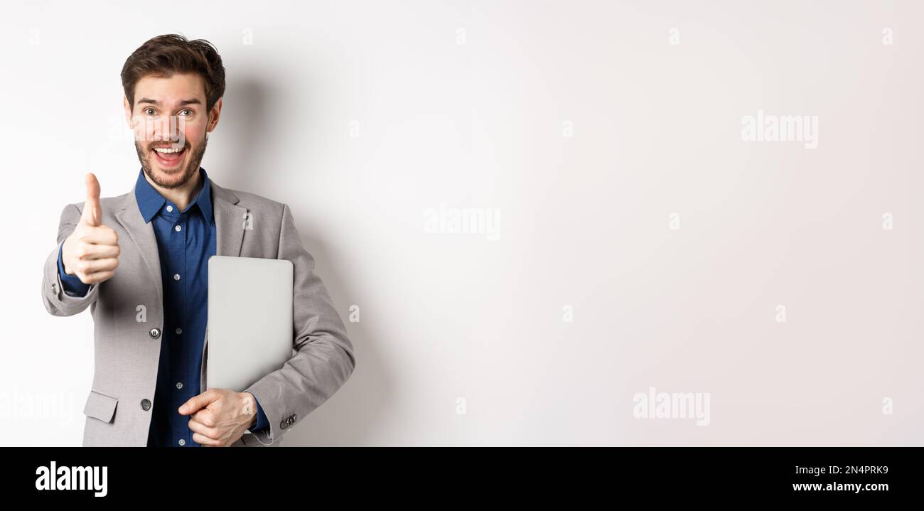 Good job. Happy smiling business man in suit holding laptop, showing ...