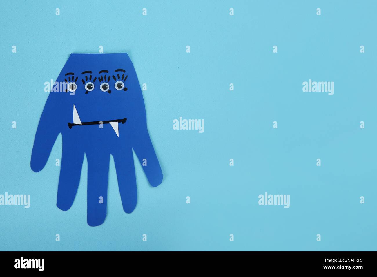 Funny hand shaped monster on light blue background, top view with space ...