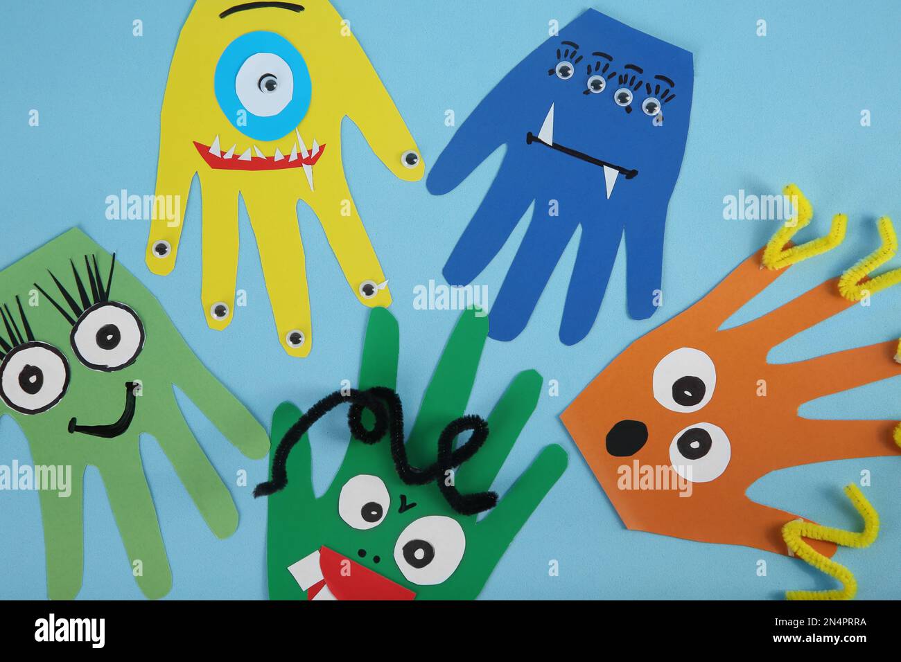 Funny hand shaped monsters on light blue background, flat lay ...