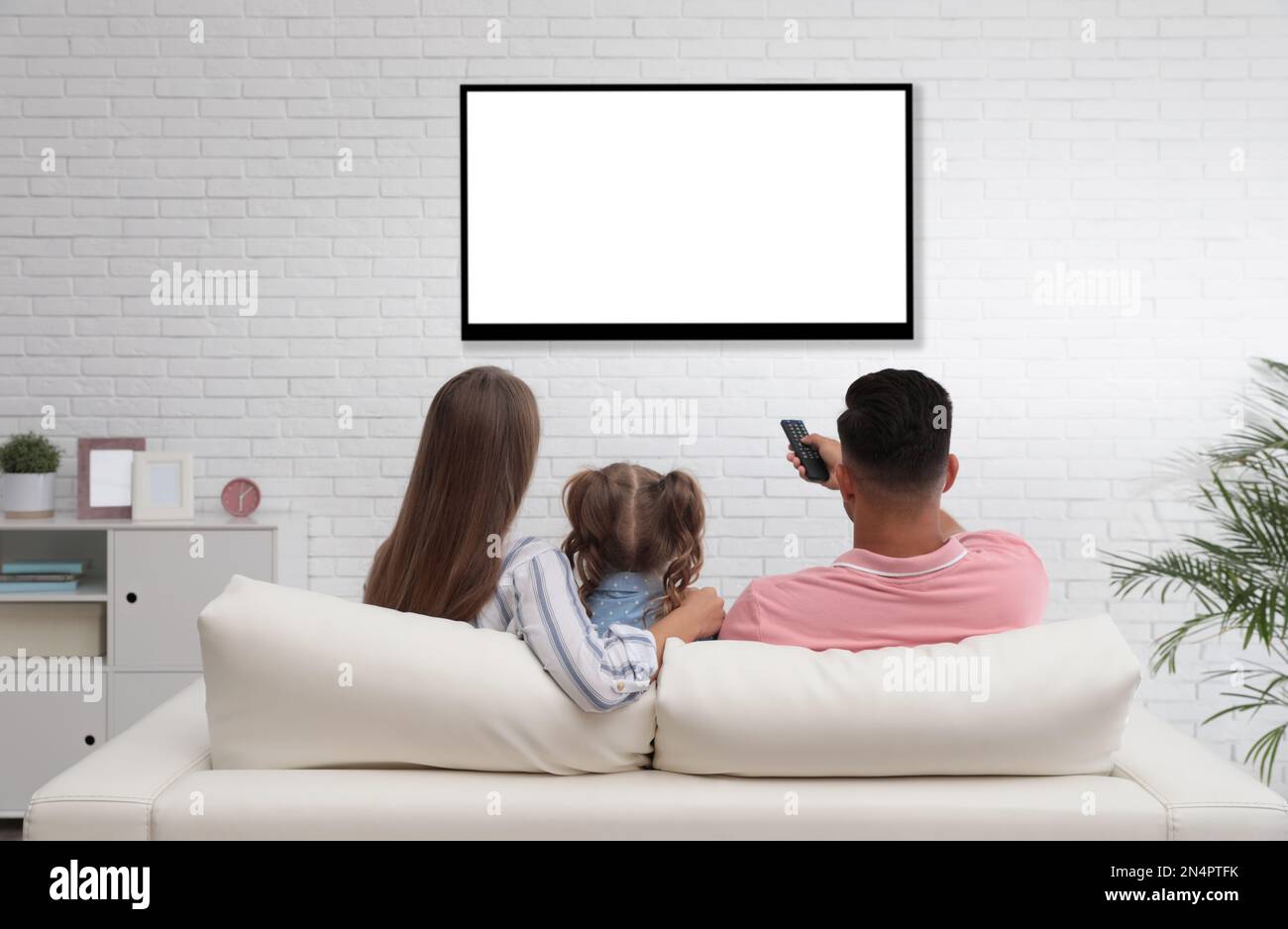 Family watching TV on sofa at home, back view Stock Photo - Alamy