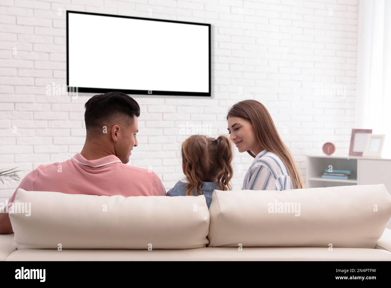 Family watching TV on sofa at home, back view Stock Photo - Alamy