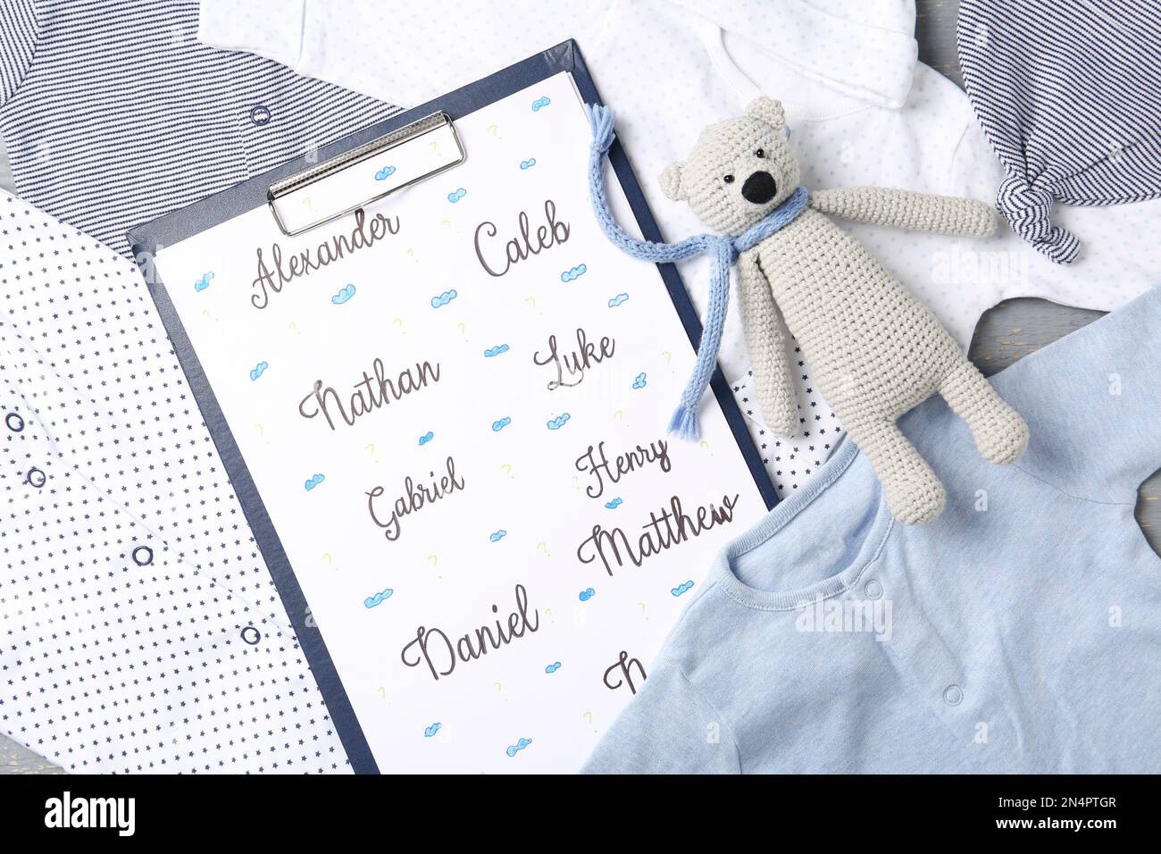 Clipboard with different baby names and toy on child's clothes, top ...
