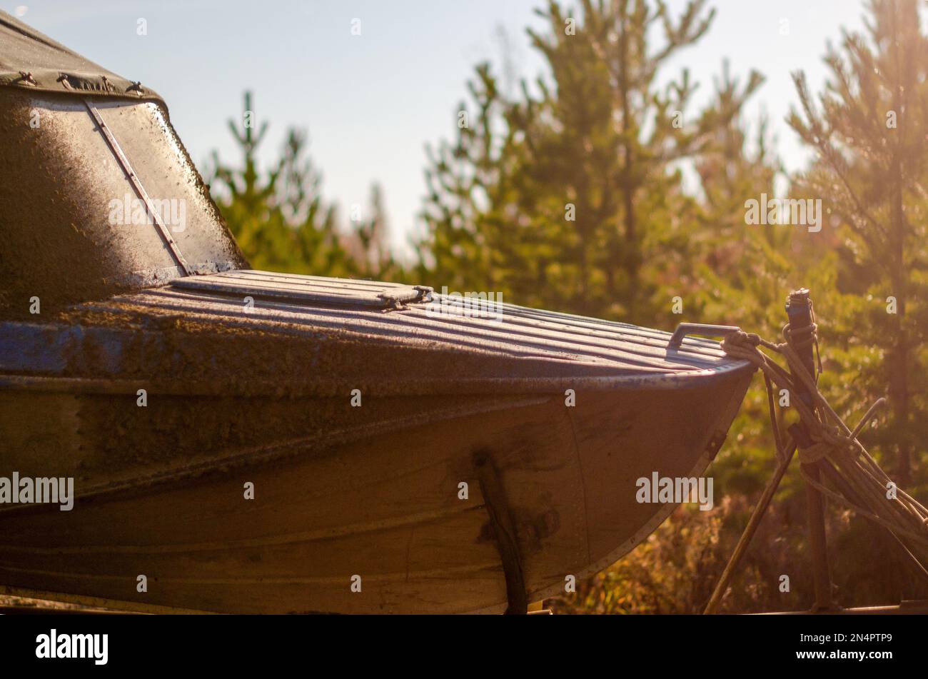 The bow of an old iron boat stands on a trailer in the early morning in ...