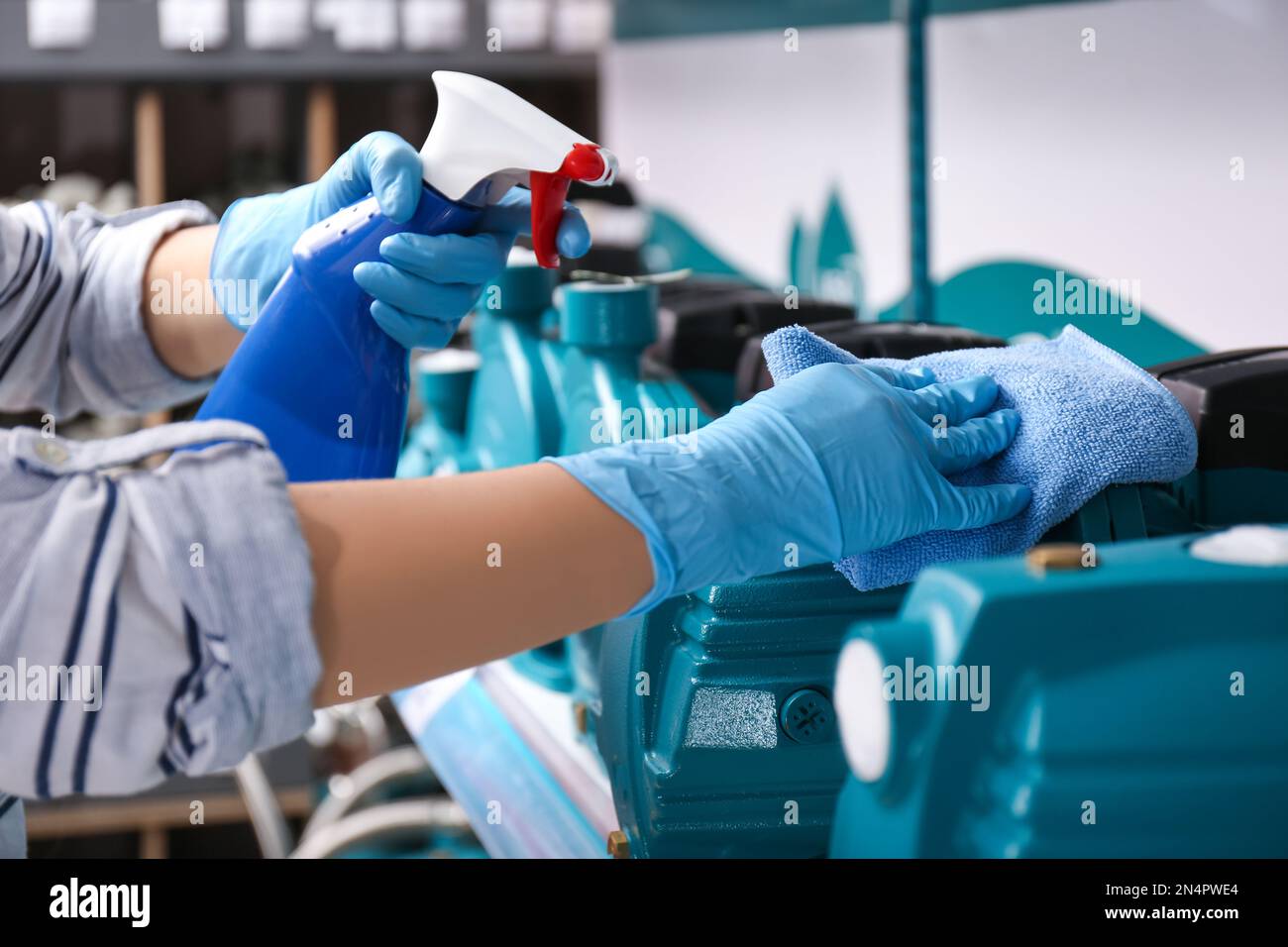 Woman cleaning water pump with rag and detergent in bathroom fixtures ...