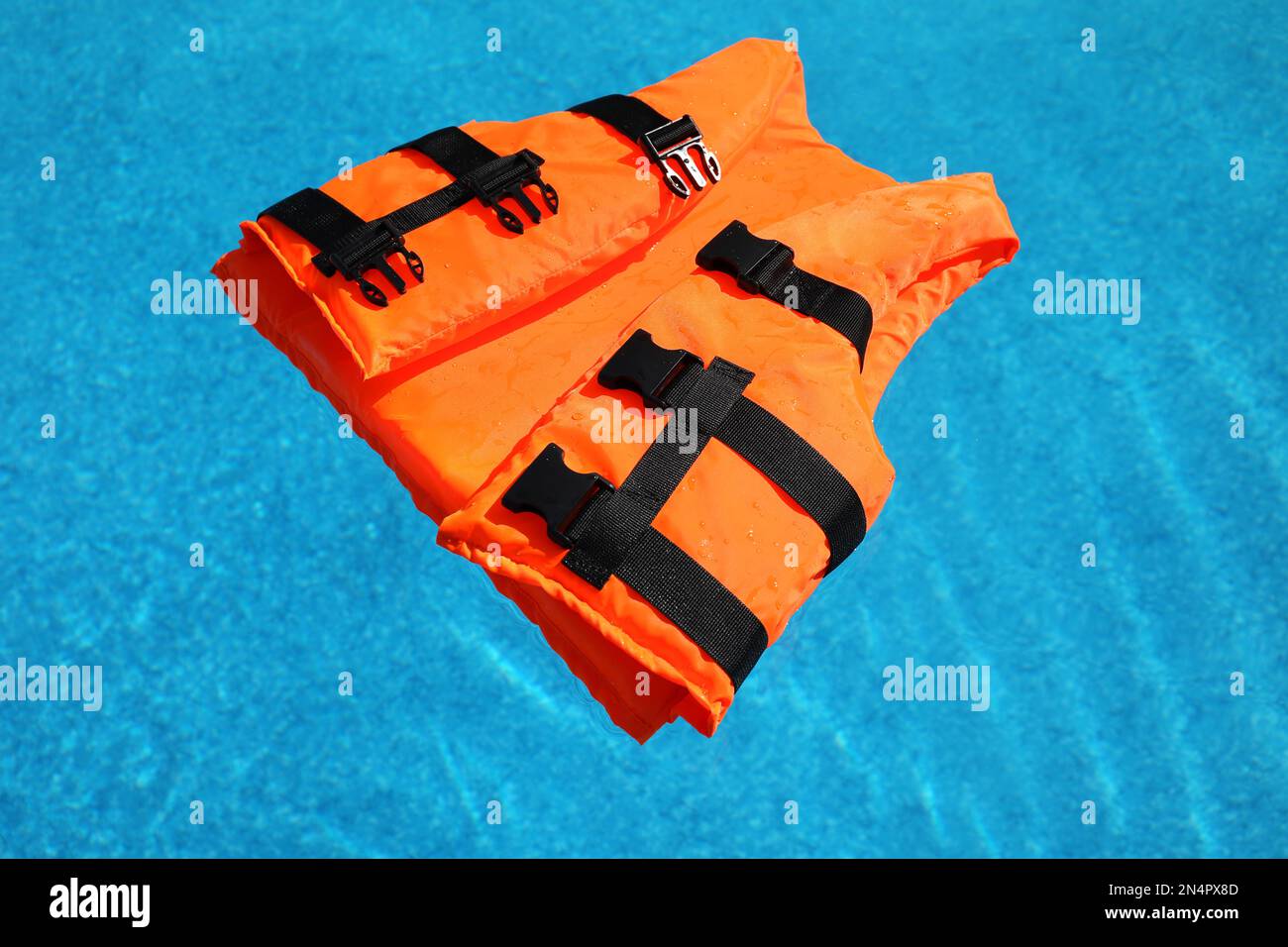 Bright orange life jacket floating in swimming pool Stock Photo - Alamy